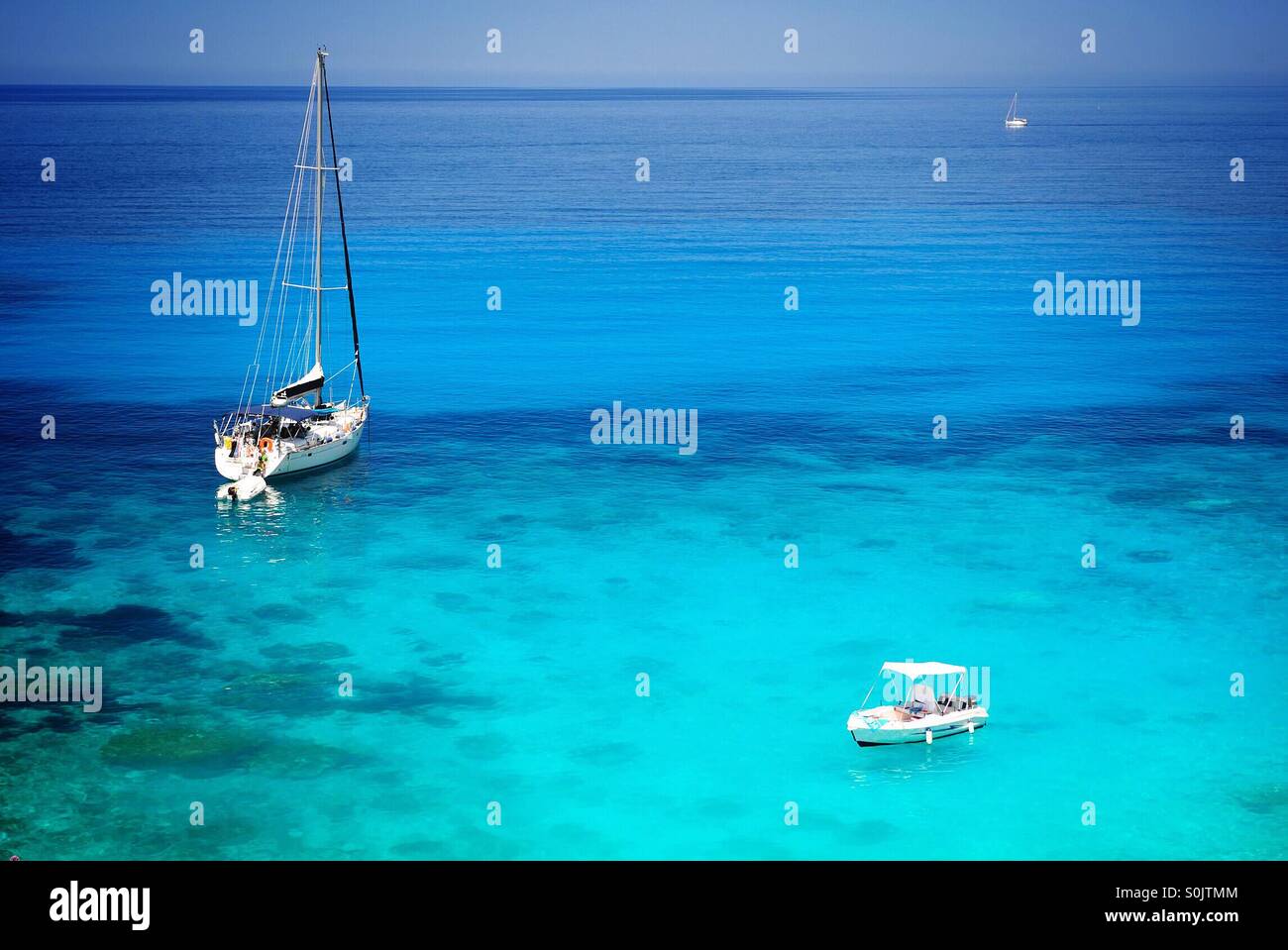 Boats in blue clear Greek water Stock Photo - Alamy