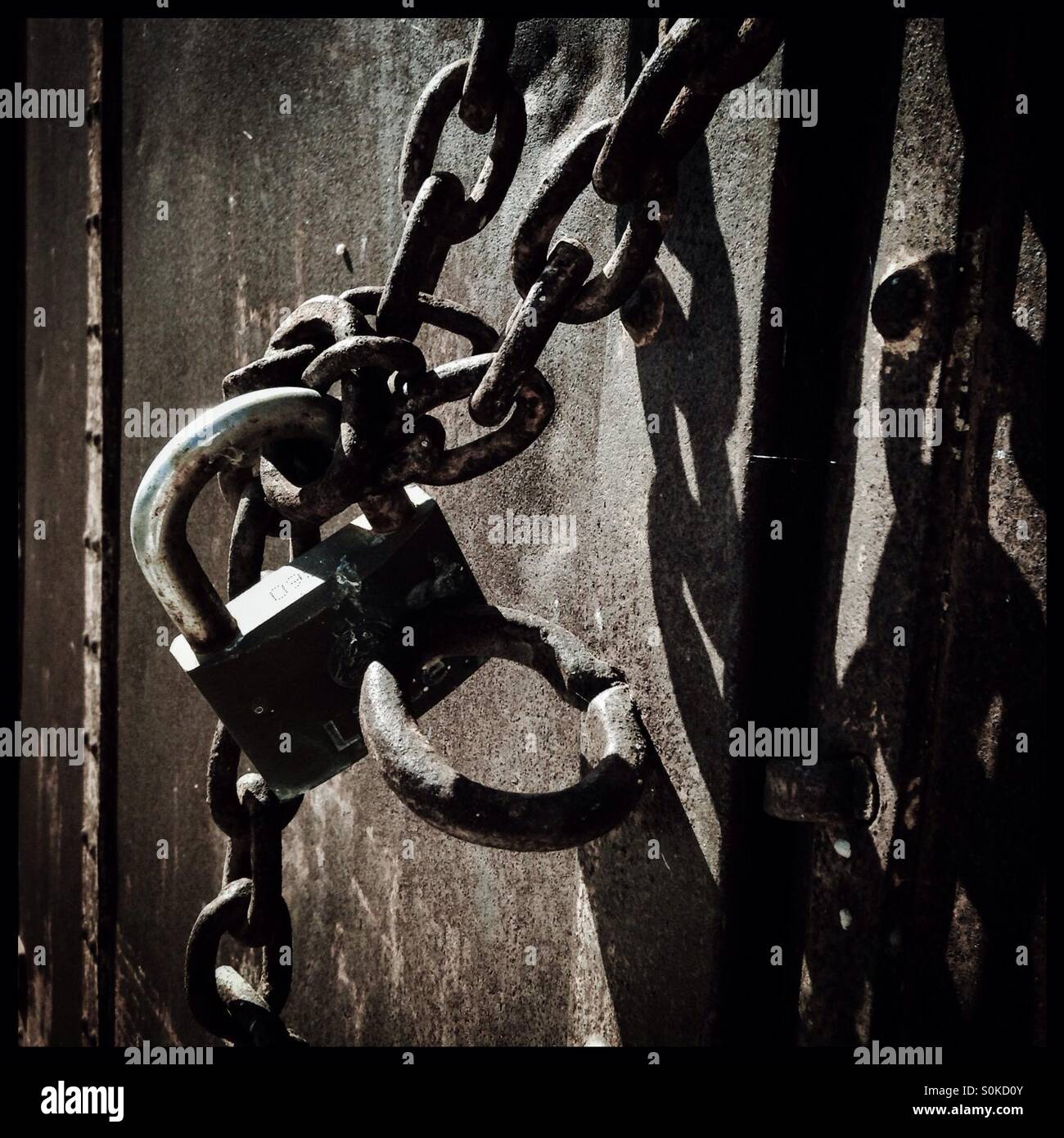Padlock and chain on a steel door, Spain Stock Photo - Alamy