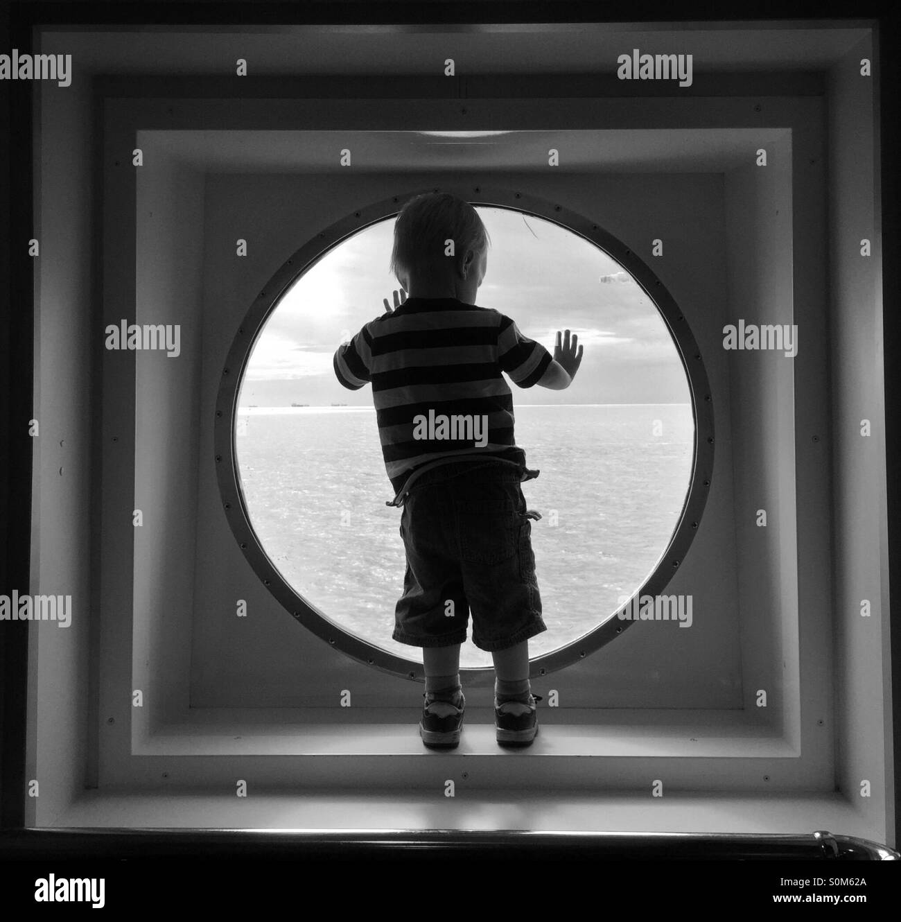 Boy looking through window Stock Photo - Alamy