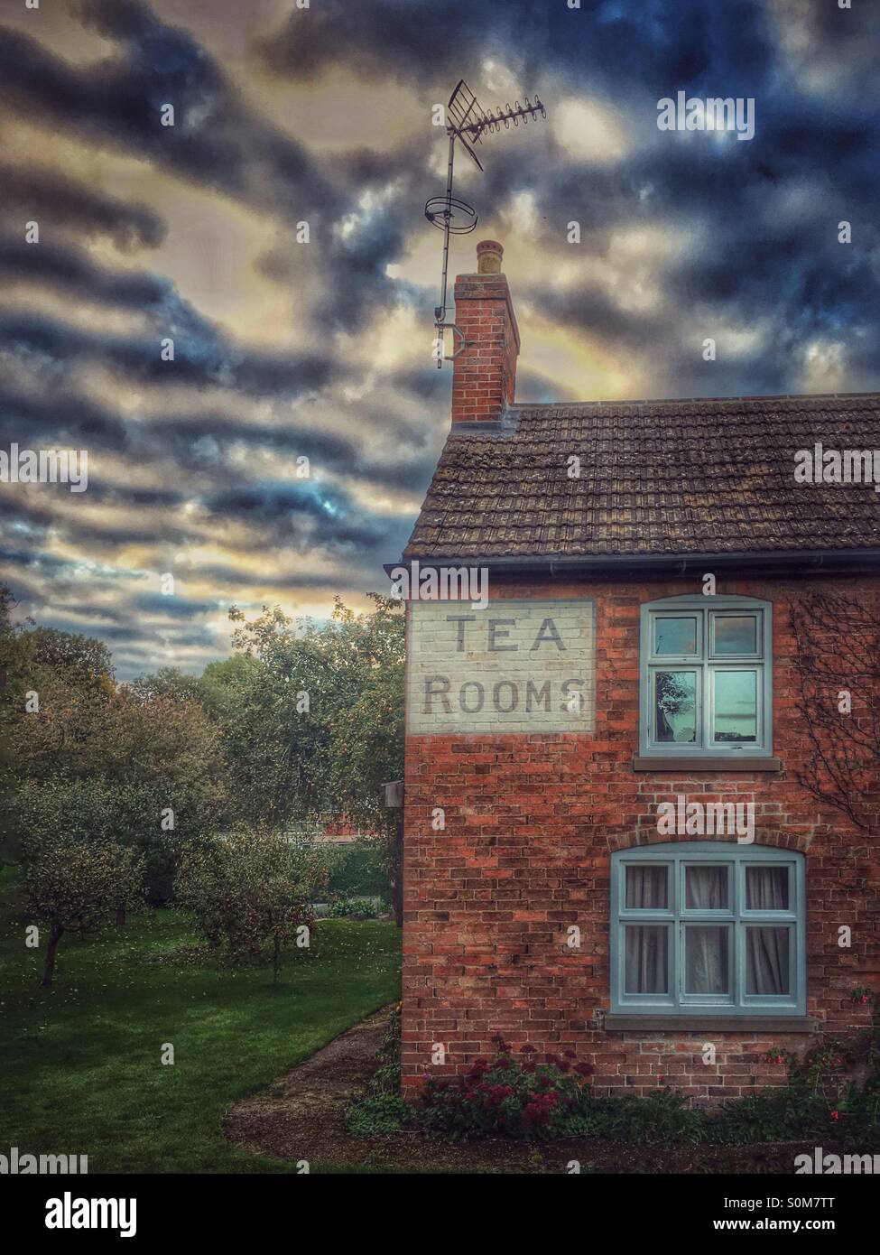 Traditional English cottage set in an orchard with a rea rooms sign ...