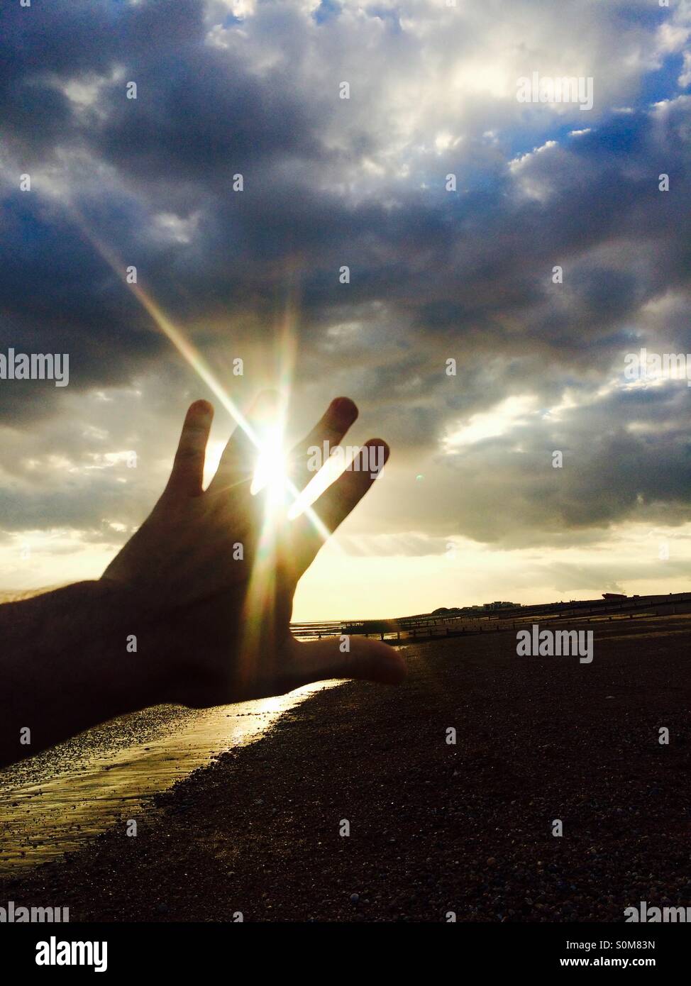 Hand in sun at beach with blue cloud sky Stock Photo - Alamy