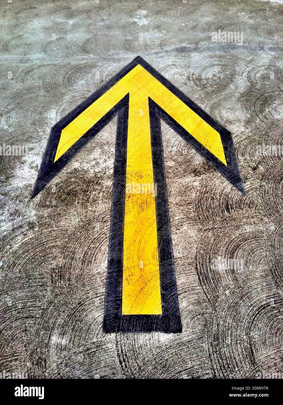 Yellow directional arrow on pavement in parking structure Stock Photo ...