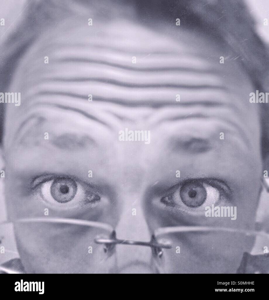 Chopped portrait of a man looking over his glasses with piercing eyes ...