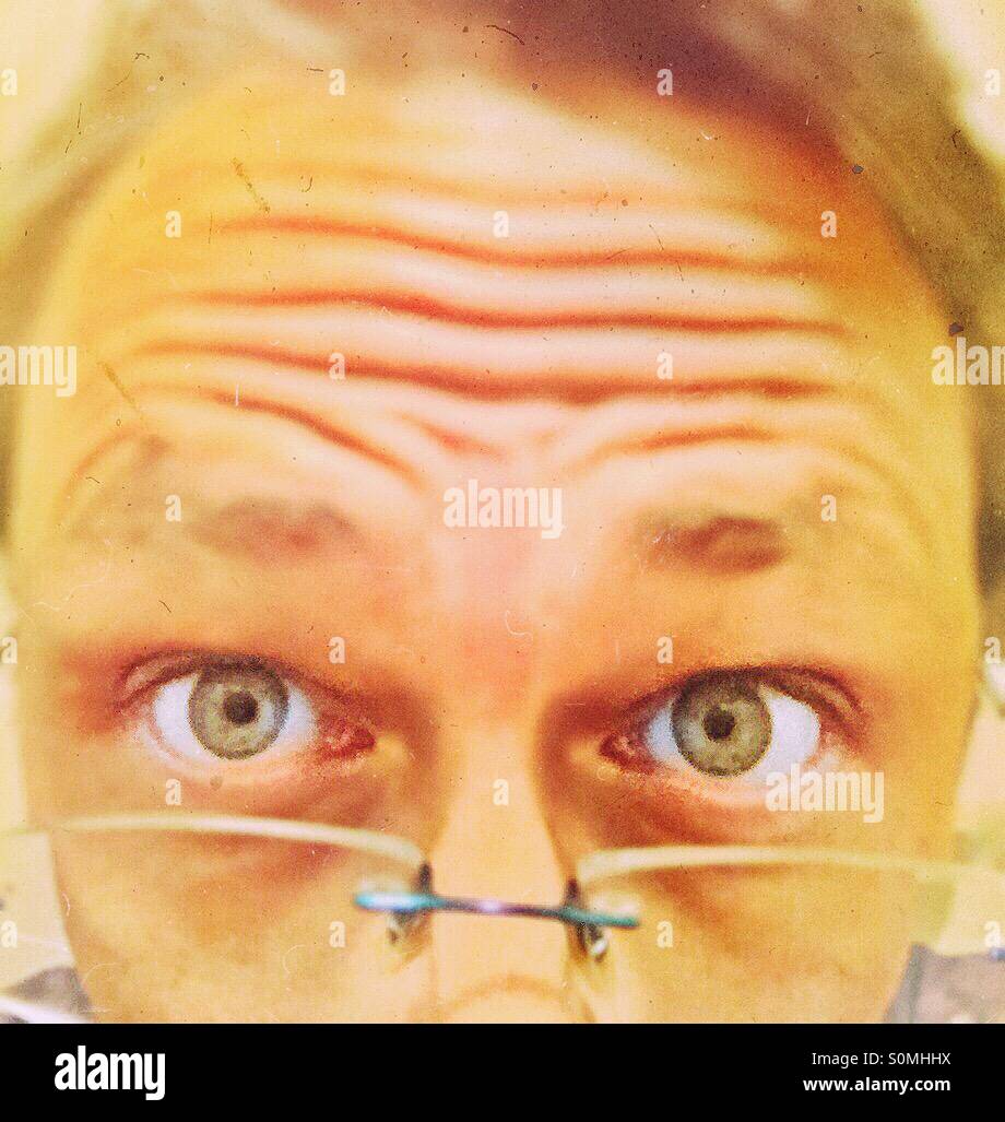 Chopped portrait of a man looking over his glasses with piercing eyes ...