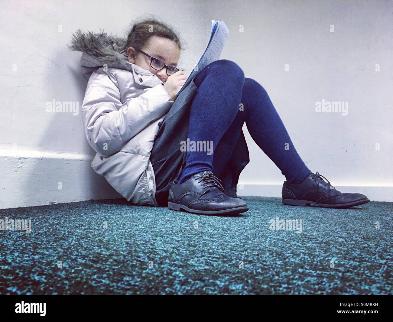 Young 8 year old girl sat in the corner on the floor drawing Stock ...