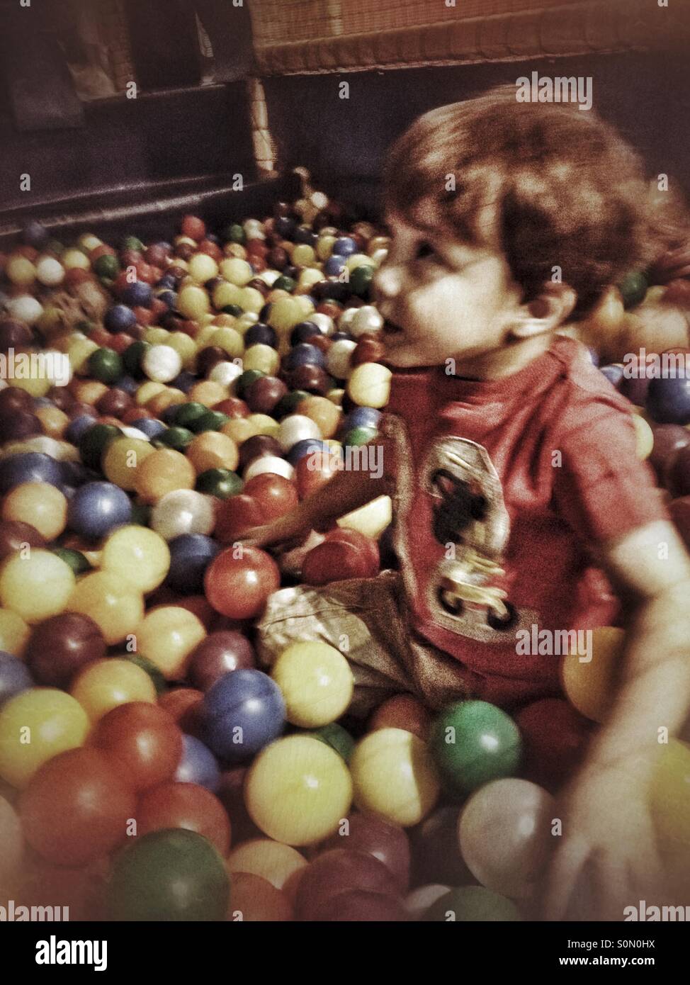 Young boy having fun in a ball pit Stock Photo - Alamy