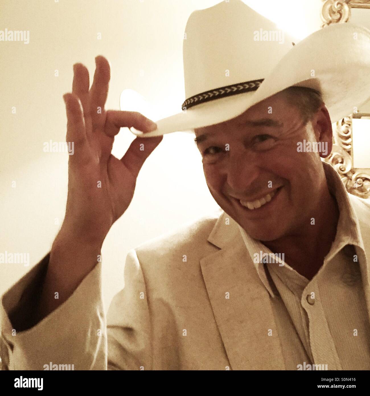 Smiling cowboy tips white hat Stock Photo - Alamy