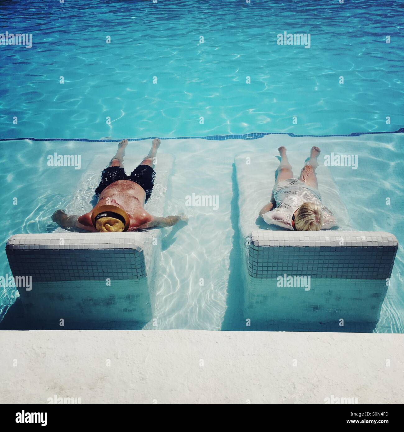 Couple relax in a swimming pool on holiday Stock Photo - Alamy