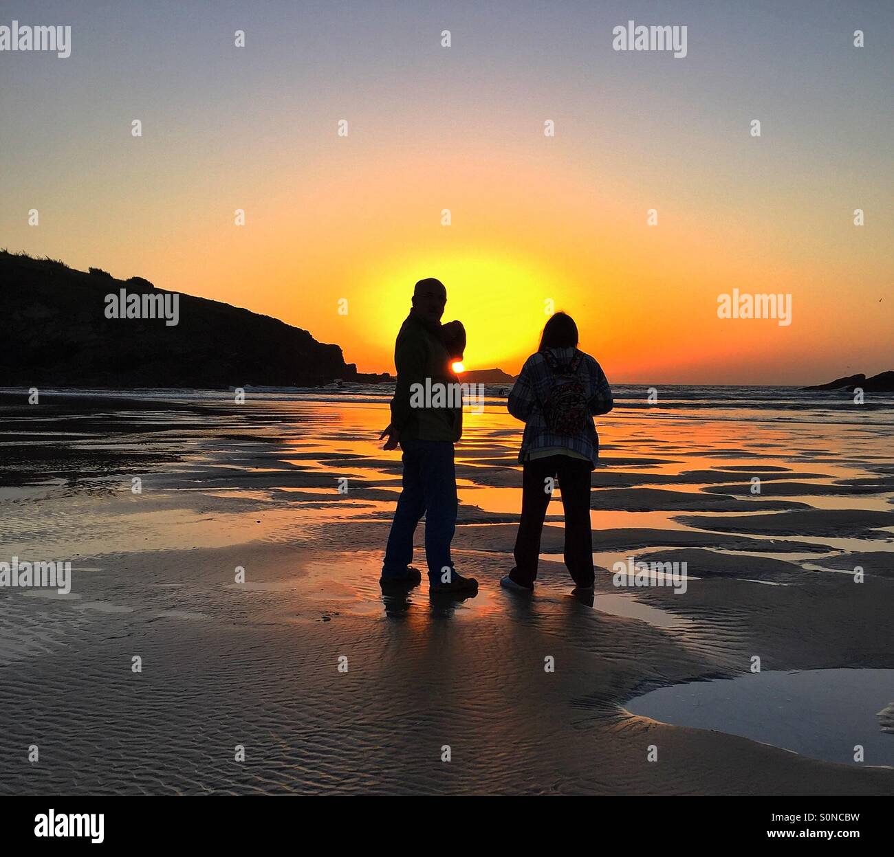 Watching the sun set on the beach Stock Photo - Alamy