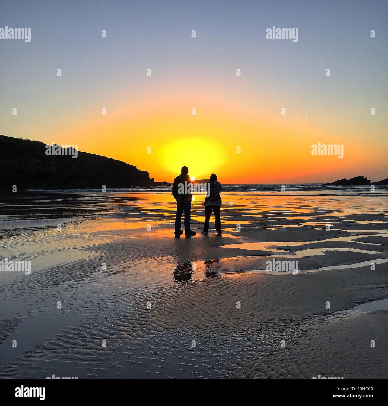 Watching the sunset on the beach Stock Photo - Alamy
