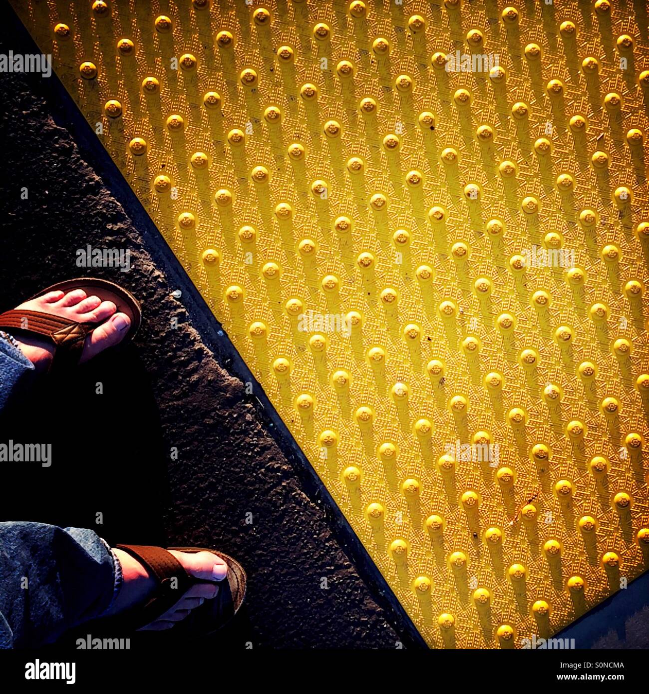 A man's feet as he stands near tactile bumps for the blind Stock Photo ...