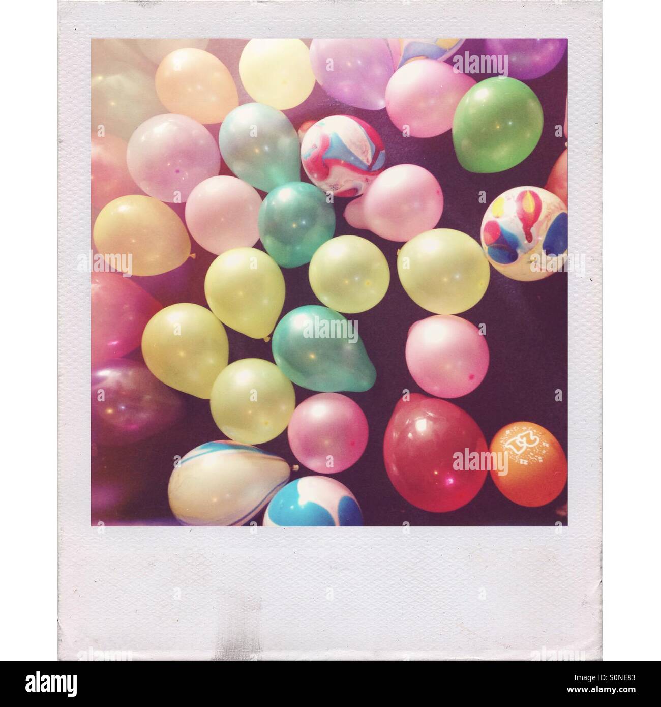 A pile of colourful party balloons with a Polaroid frame Stock Photo ...