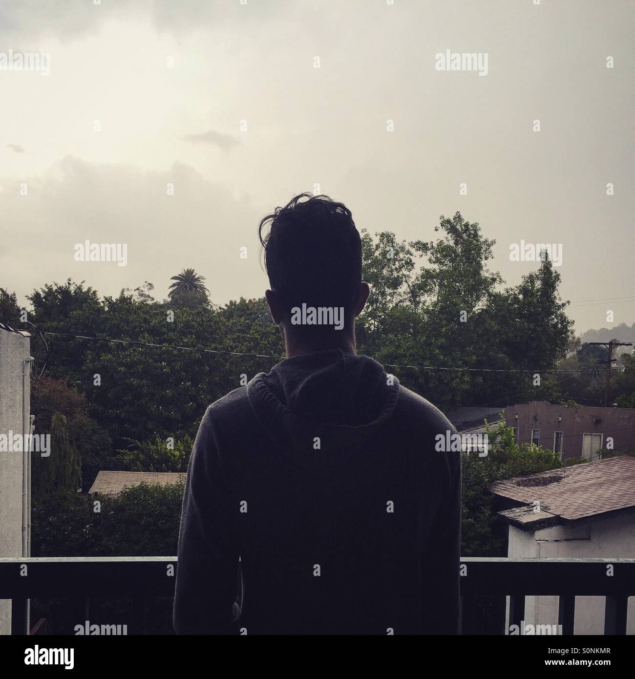 Man on balcony watching weather roll in Stock Photo - Alamy