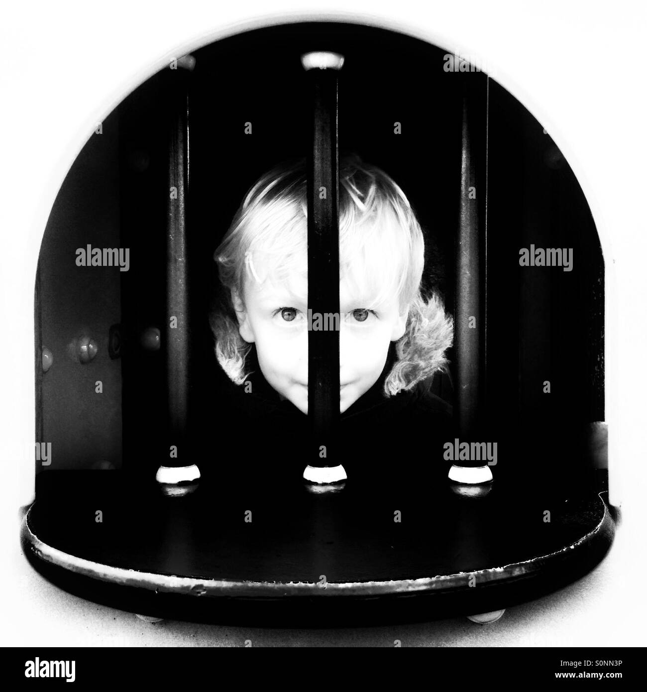 Boy looking through bars in black and white Stock Photo - Alamy