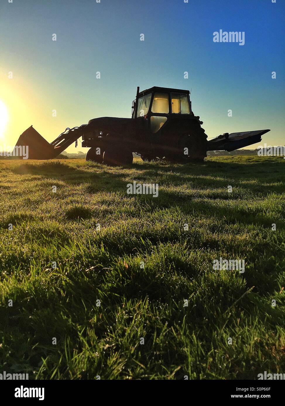 Tractor at sunrise Stock Photo - Alamy