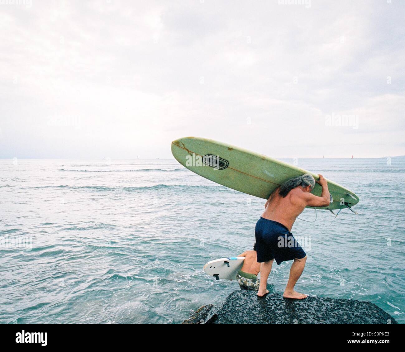 Longboard Surfer entering the Ocean from a Jetty Stock Photo - Alamy