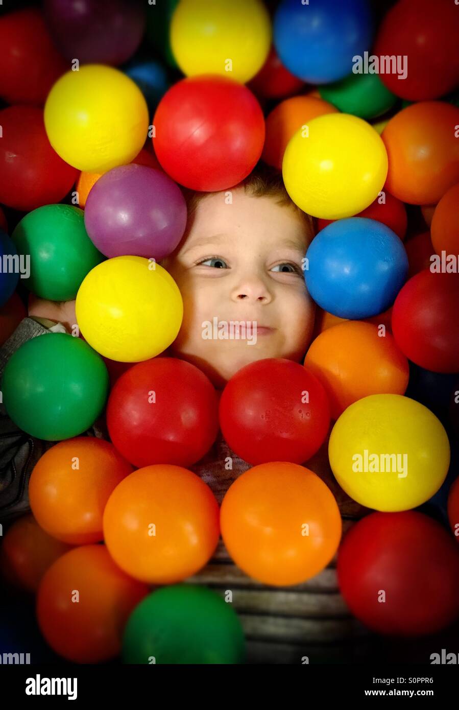 Boy in Coloured Balls Stock Photo - Alamy