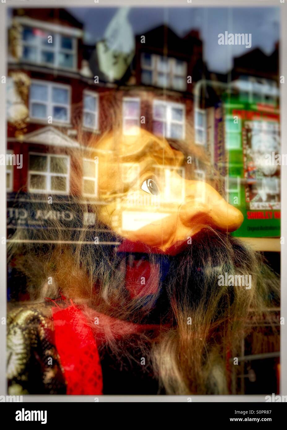Puppet in a shop window display. With reflections of the high street on ...