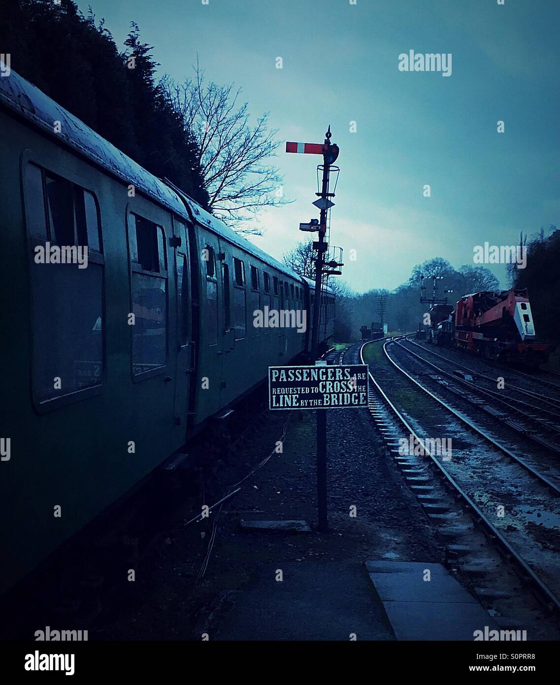 Passengers crossing sign with train to the side Stock Photo - Alamy