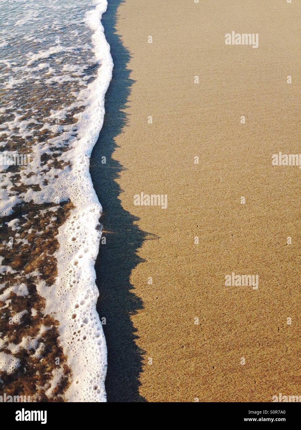 Wave moving up a sandy beach Stock Photo - Alamy