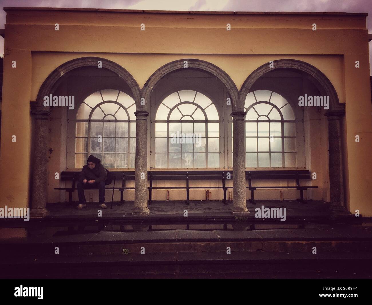 A person sits under arches Stock Photo - Alamy