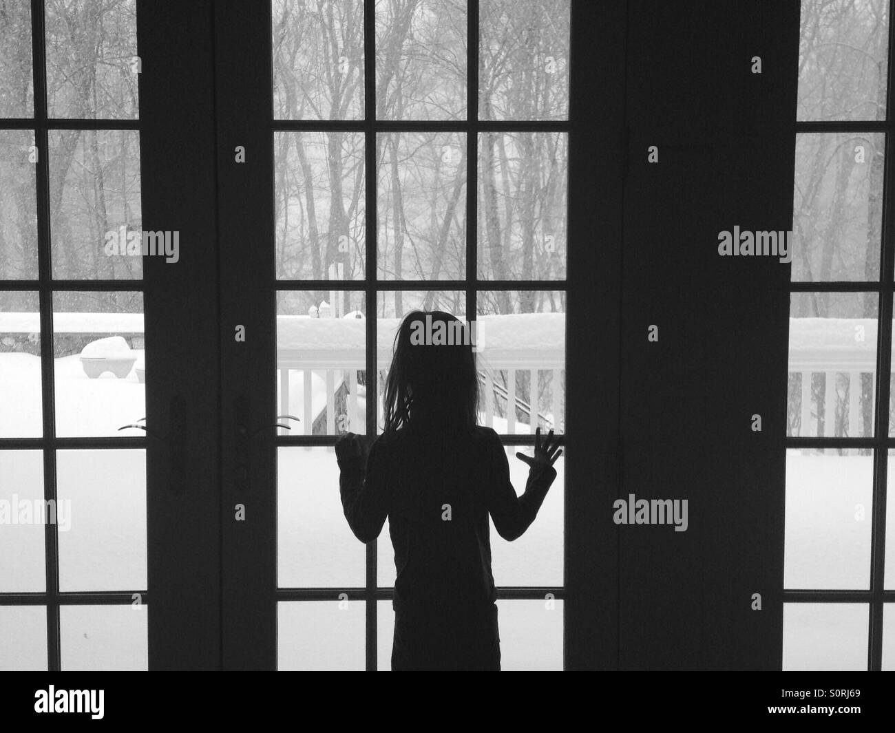 Girl looking out window at snow Stock Photo - Alamy