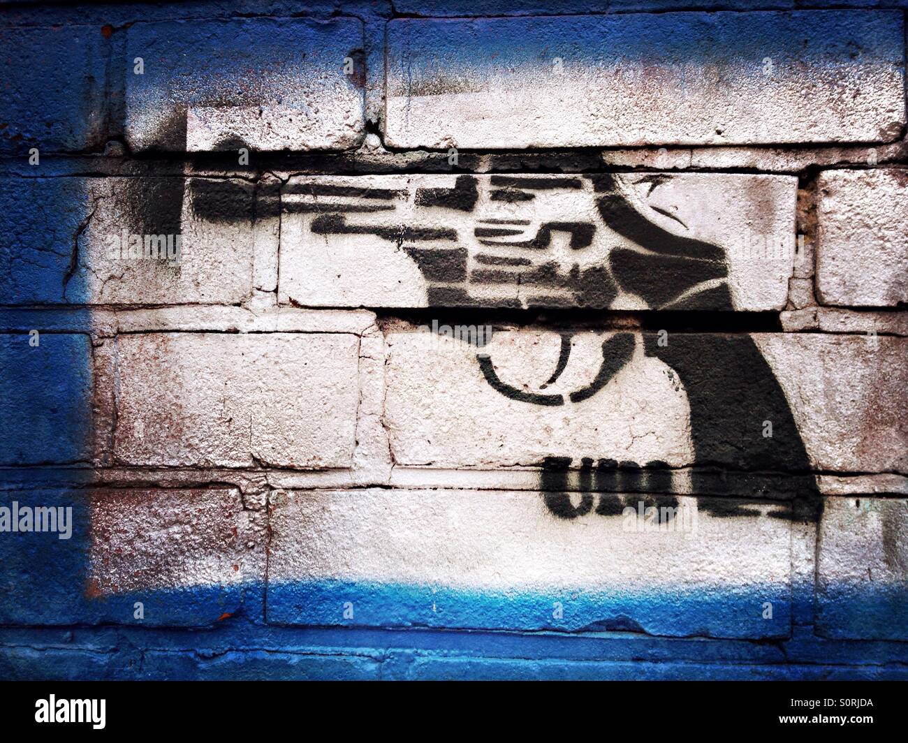 A stencil graffiti of a revolver on a brick wall in Berlin, Germany ...