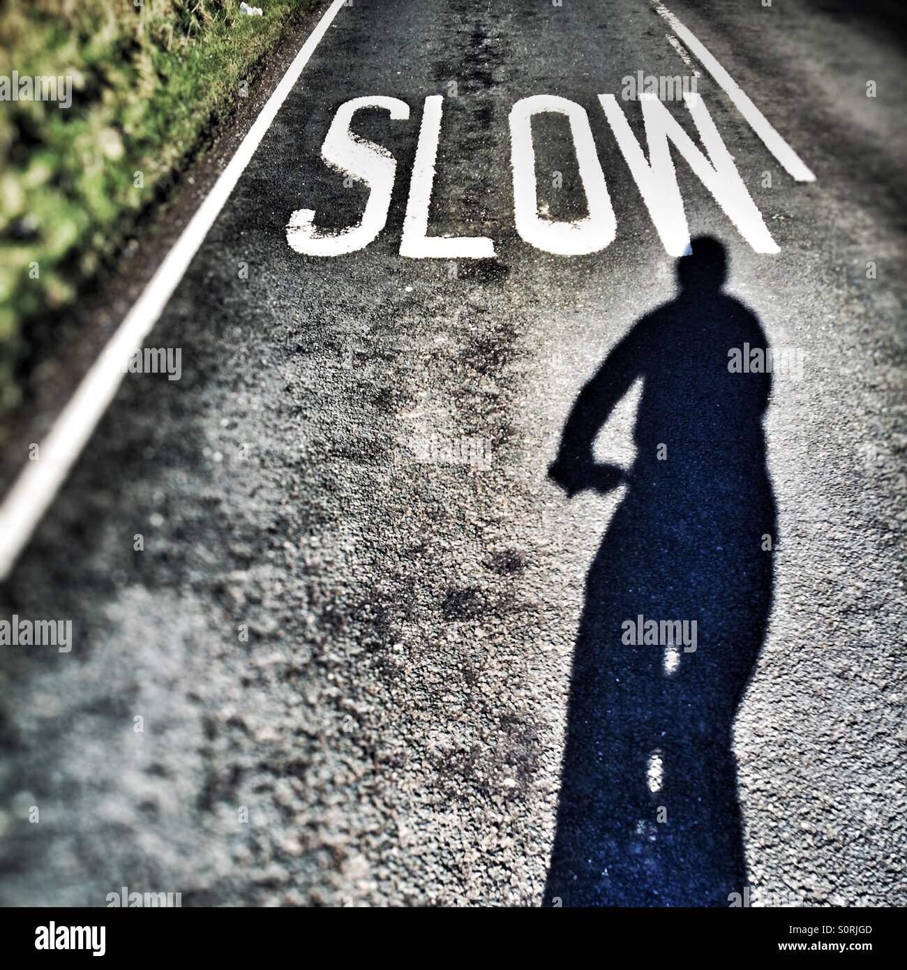 Cyclist shadow Selfie approaching a slow sign on the road Stock Photo ...