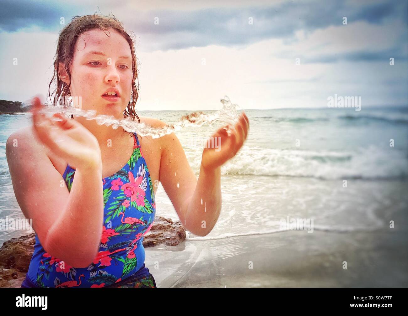 Girl in swimsuit playing with water at the beach in summer Stock Photo ...