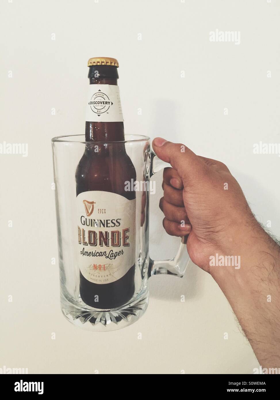 Beer love. Holding Guinness beer bottle in beer mug Stock Photo - Alamy