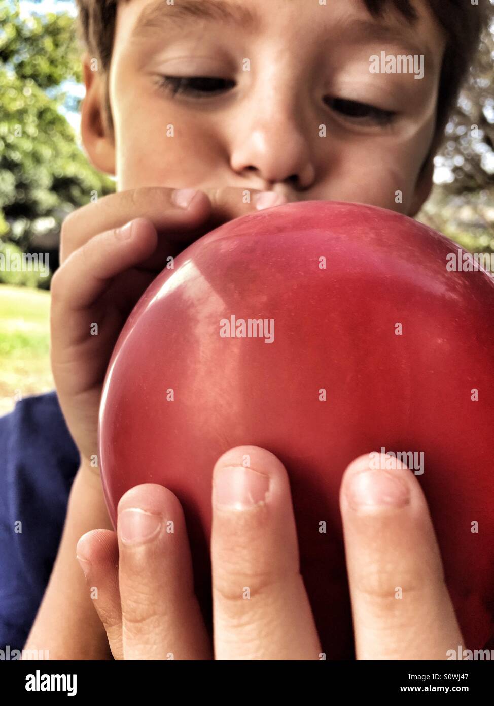 Boy blowing up red balloon hi-res stock photography and images - Alamy