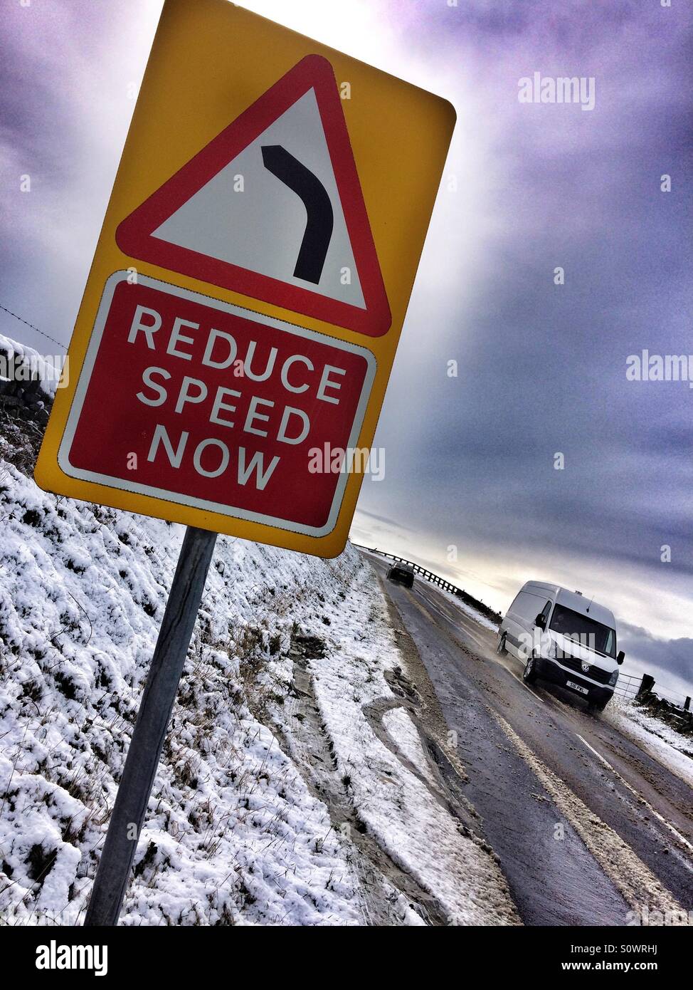 Driving in snow reduce speed bend ahead Stock Photo - Alamy