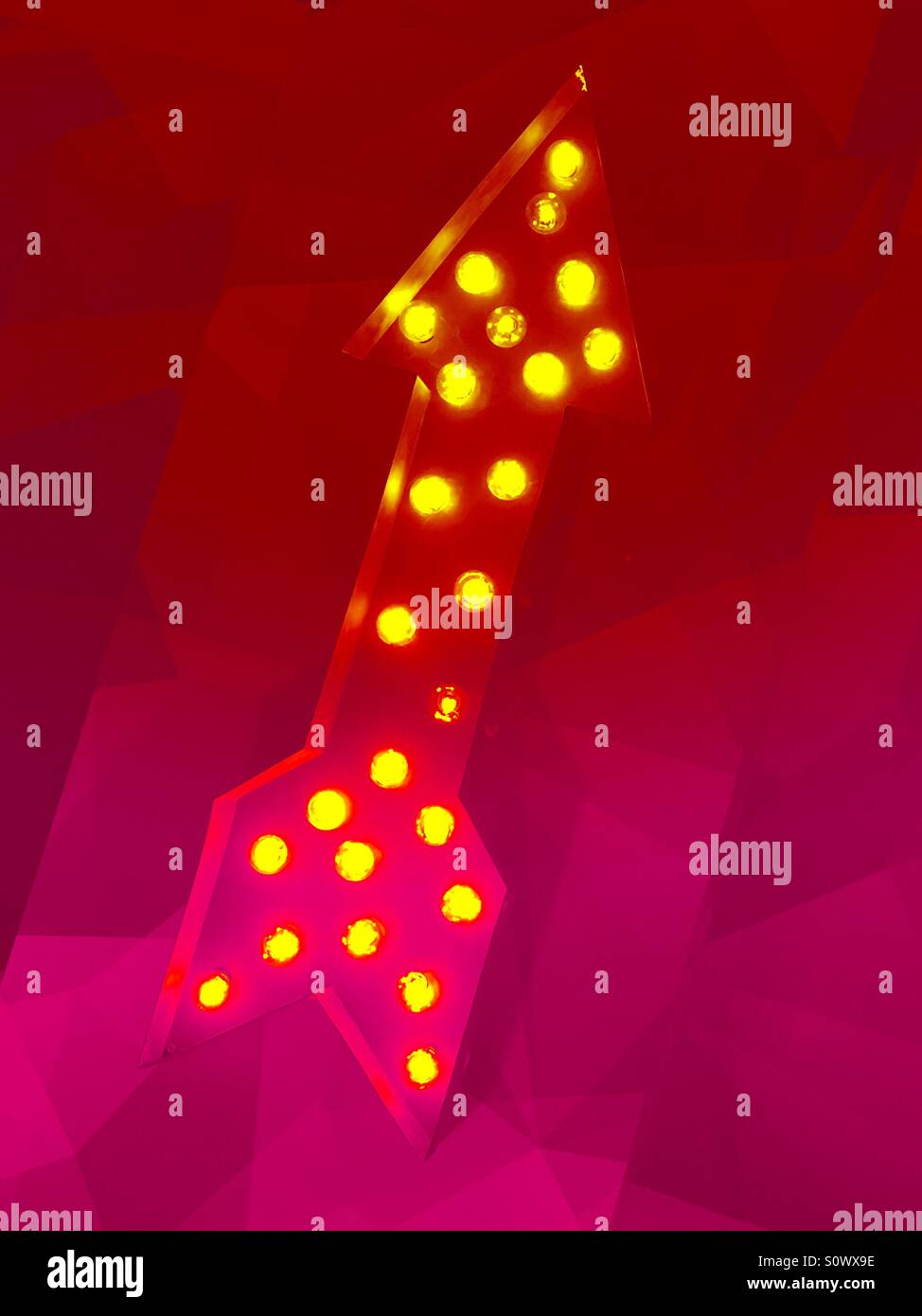Brightly lit red arrow on red background points up Stock Photo - Alamy