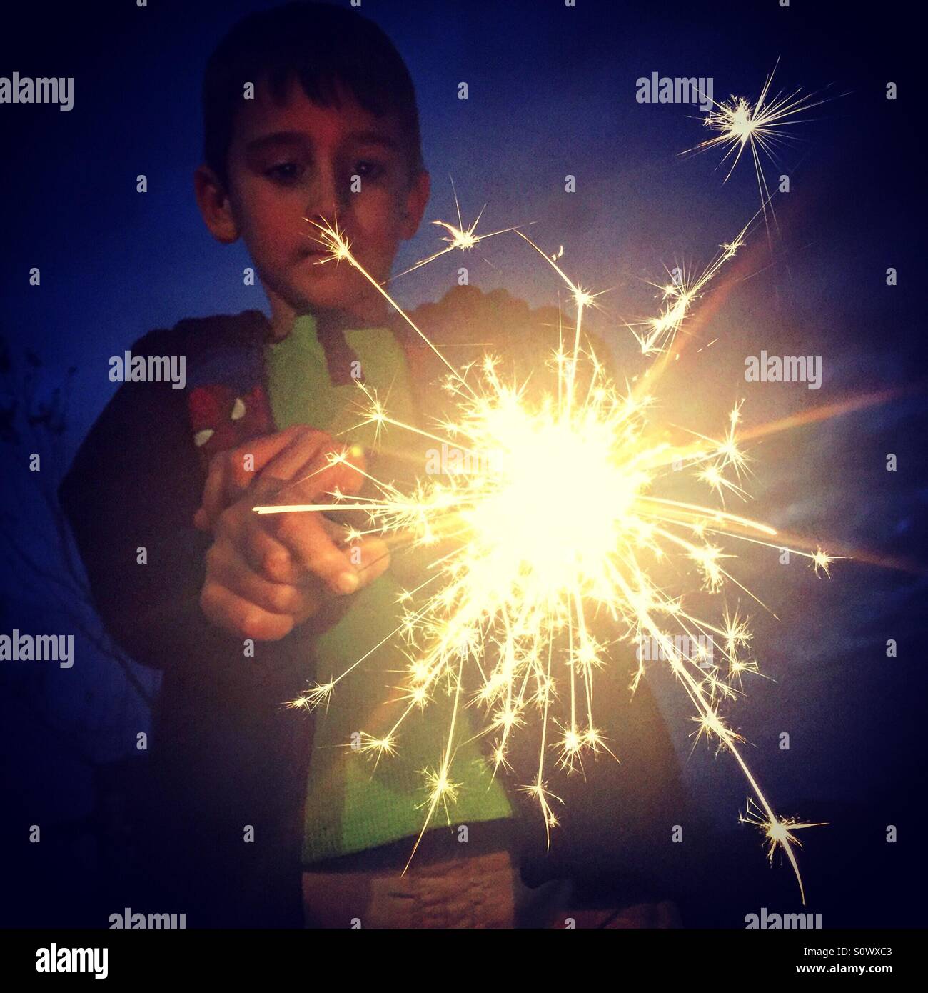 Celebrate! Young boy holds a sparkler in celebration on a summer ...