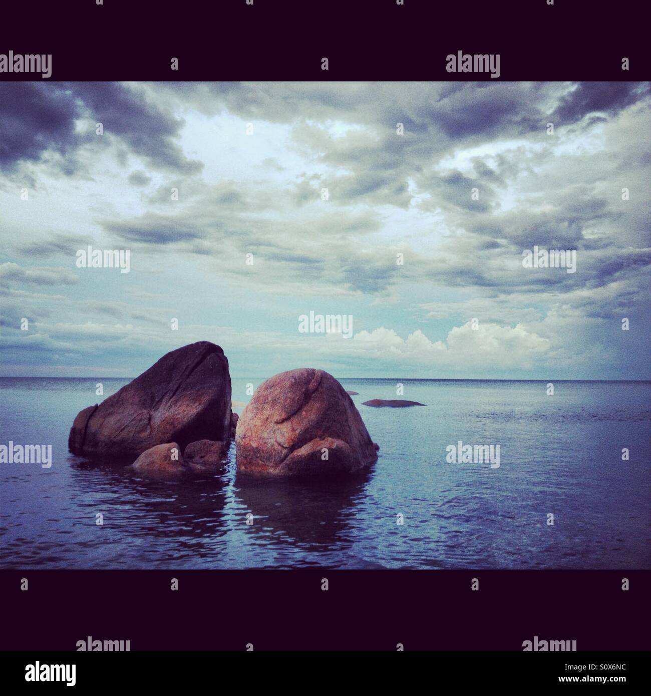 Two rocks in the ocean with blue sky Stock Photo - Alamy