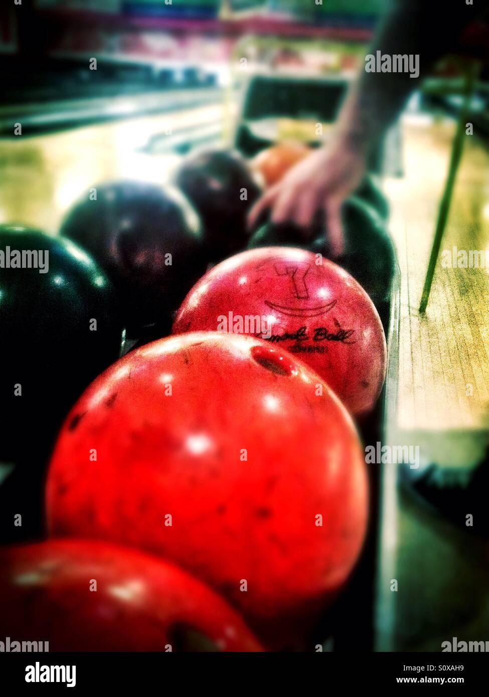 A person selects a bowling ball from the ball return at a bowling alley ...