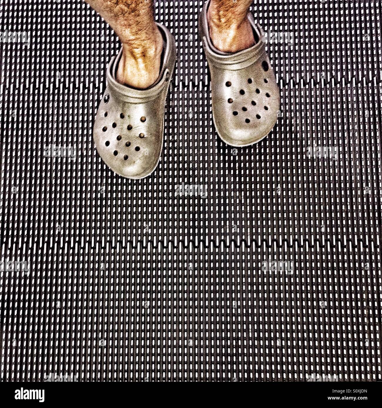 Man wearing plastic clogs on an escalator Stock Photo - Alamy