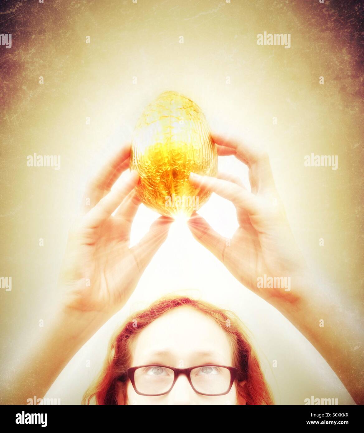 Young girl holding aloft a golden Easter egg Stock Photo - Alamy