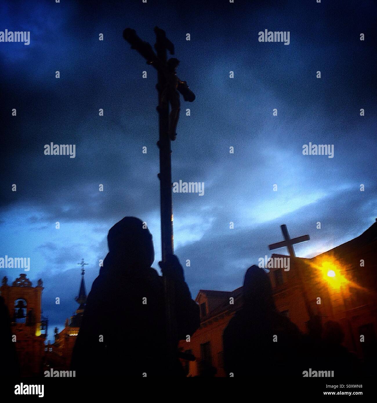A hooded penitent holds a crucifix during Easter Holy Week in Astorga ...