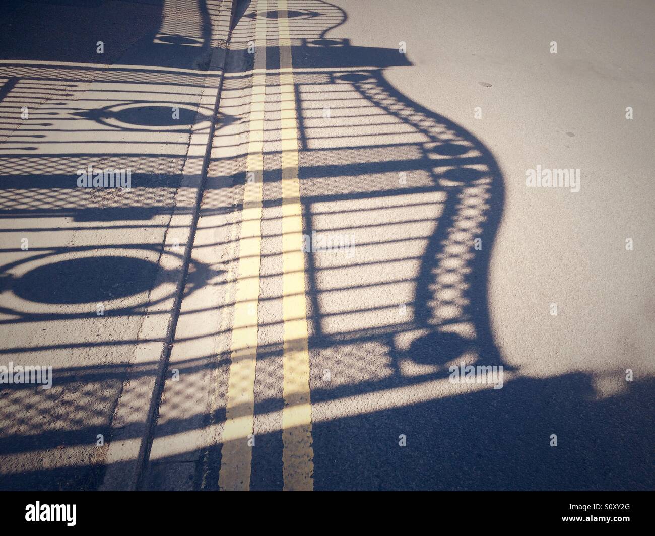 Shadow of a gate across a double yellow line on a road Stock Photo - Alamy