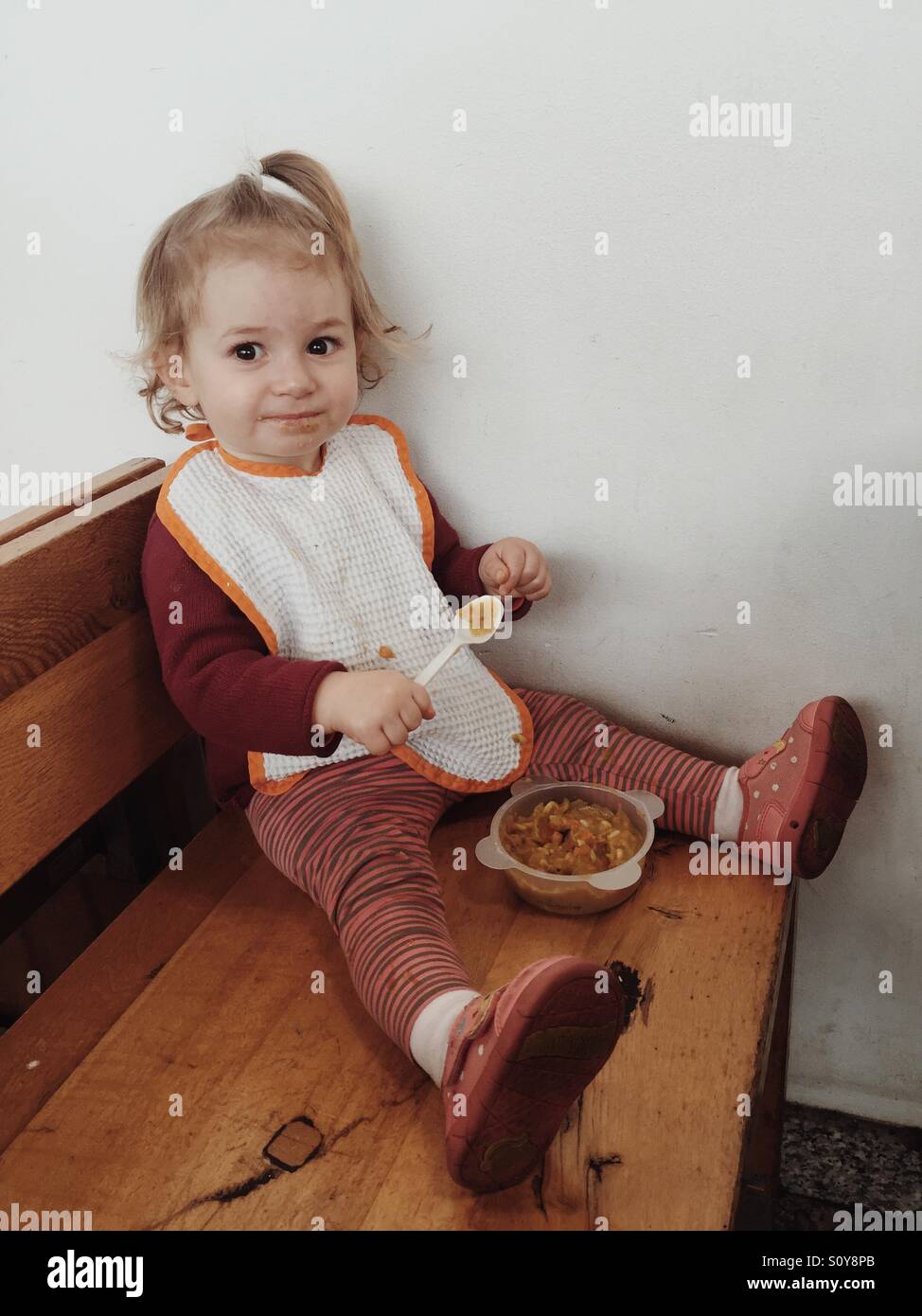 Baby girl eating by herself Stock Photo - Alamy