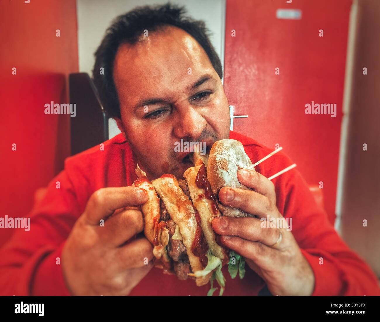 Man eating unhealthy burger Stock Photo - Alamy