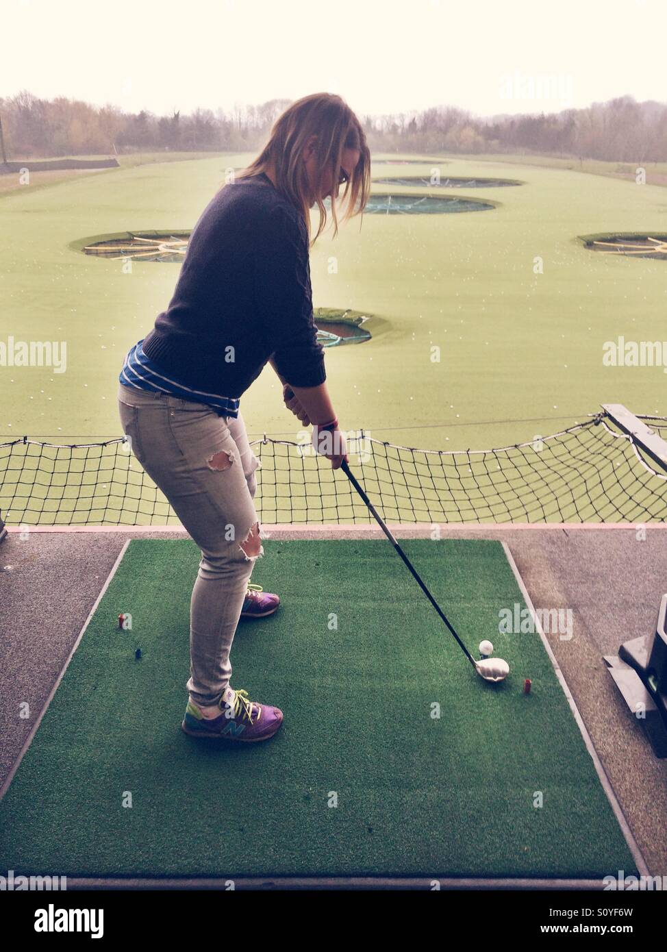Girl playing golf at a driving range Stock Photo - Alamy
