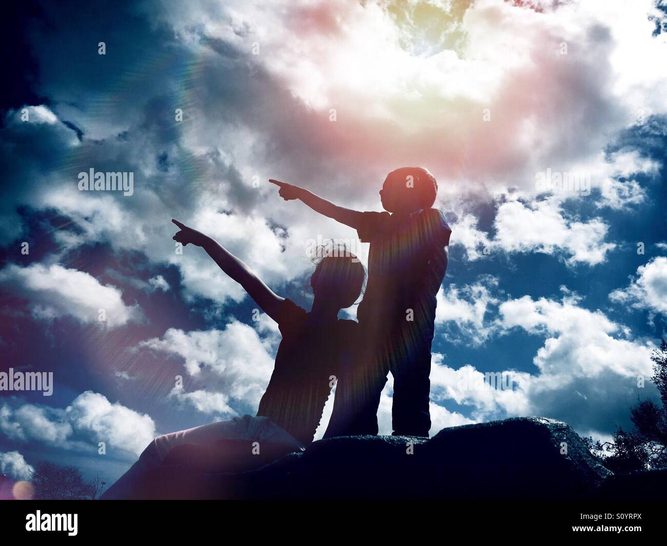 Children on a rock pointing into distance Stock Photo - Alamy