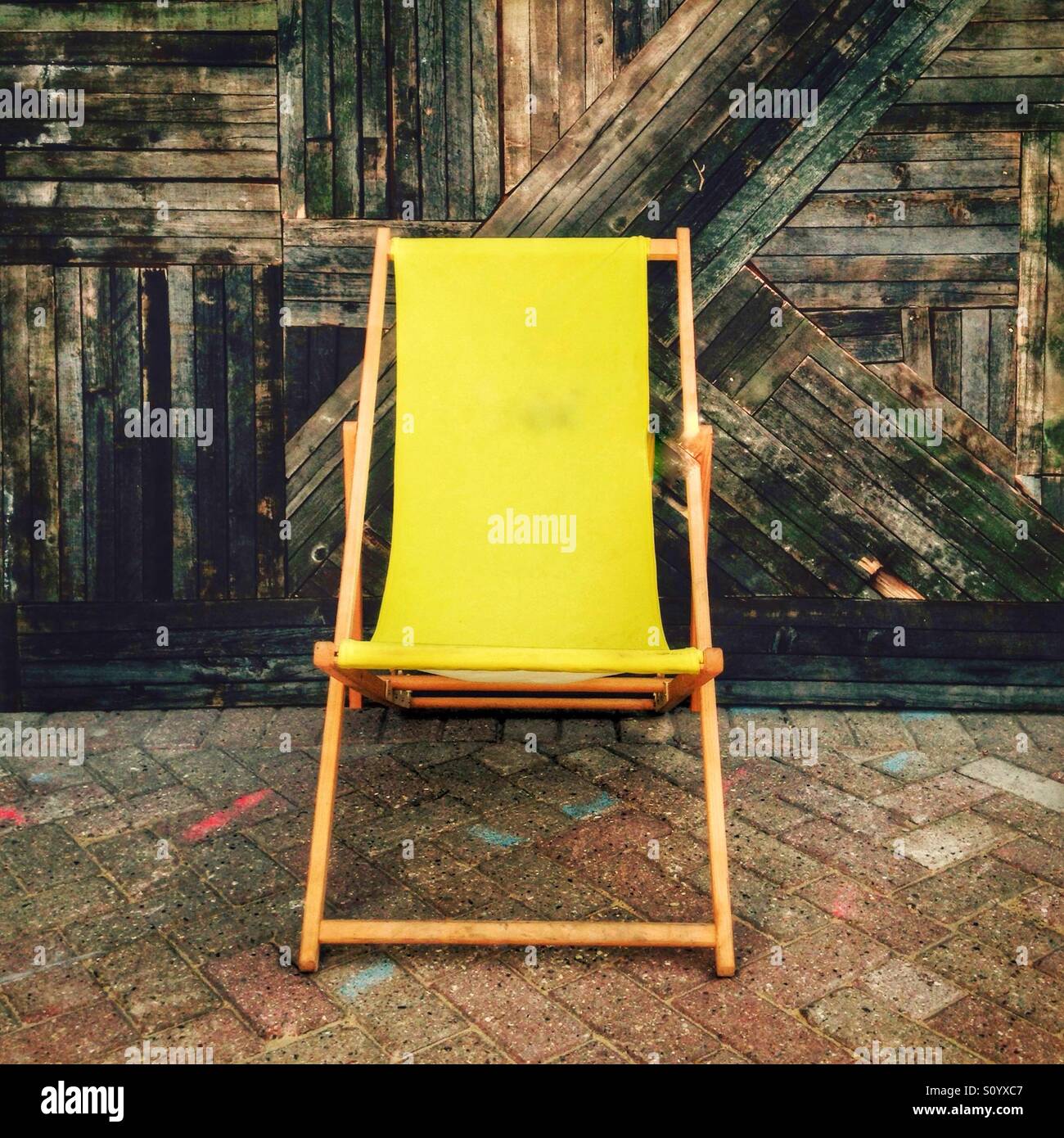 Bright yellow deck chair against weathered wood Stock Photo - Alamy