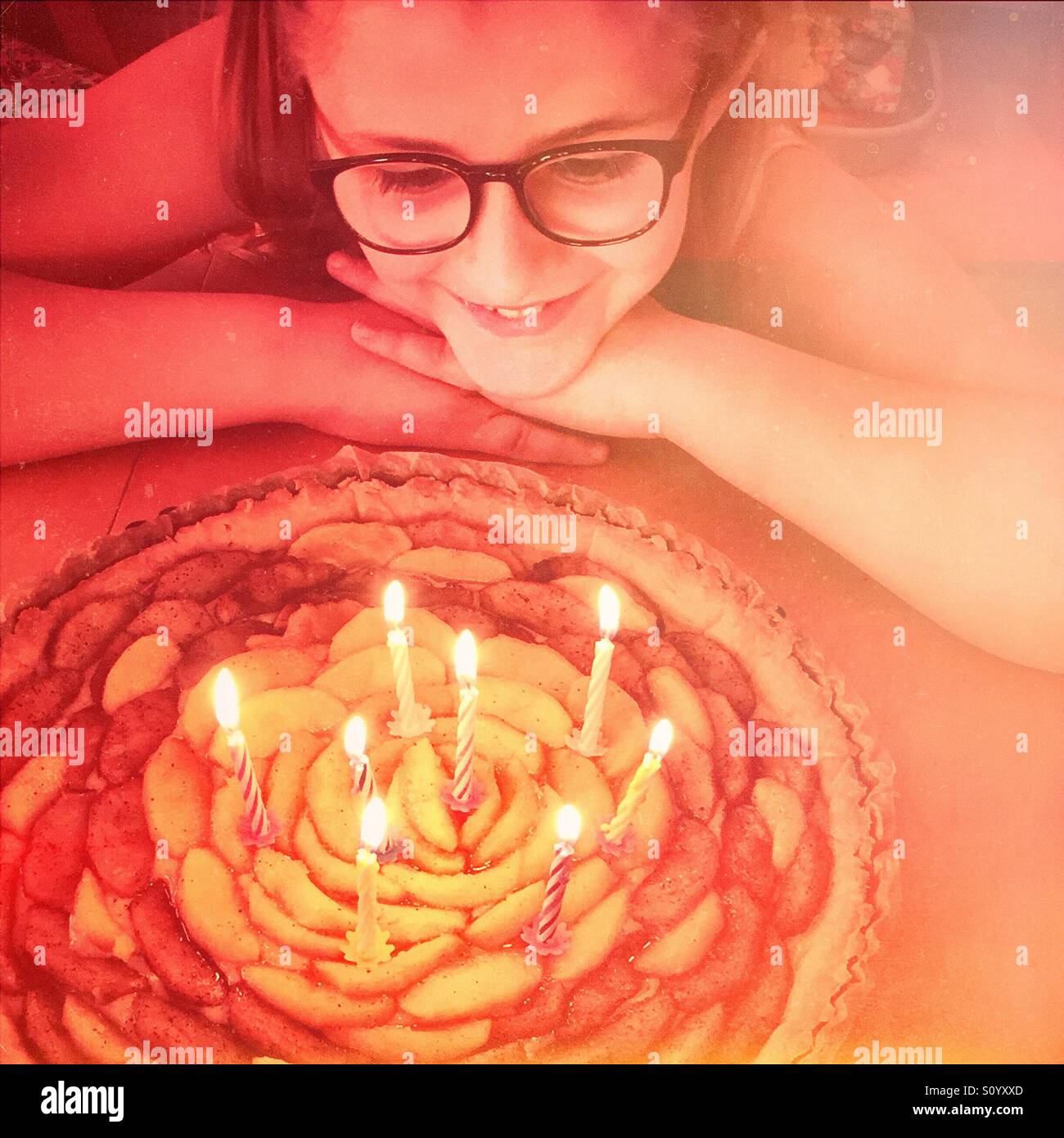 Little girl with eyeglasses looking at her birthday apple pie with 8 ...