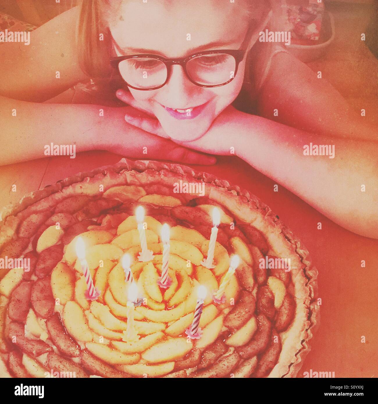 Little girl with eyeglasses looking at her birthday apple pie with 8 ...