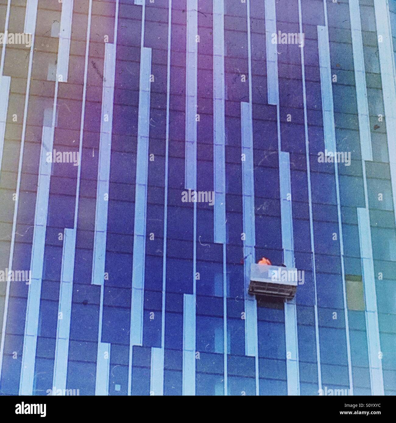 Building worker doing maintenance job against a skyscraper glass facade ...