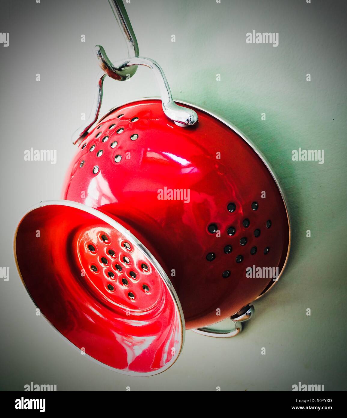 Red colander hanging on a hook in a kitchen Stock Photo - Alamy