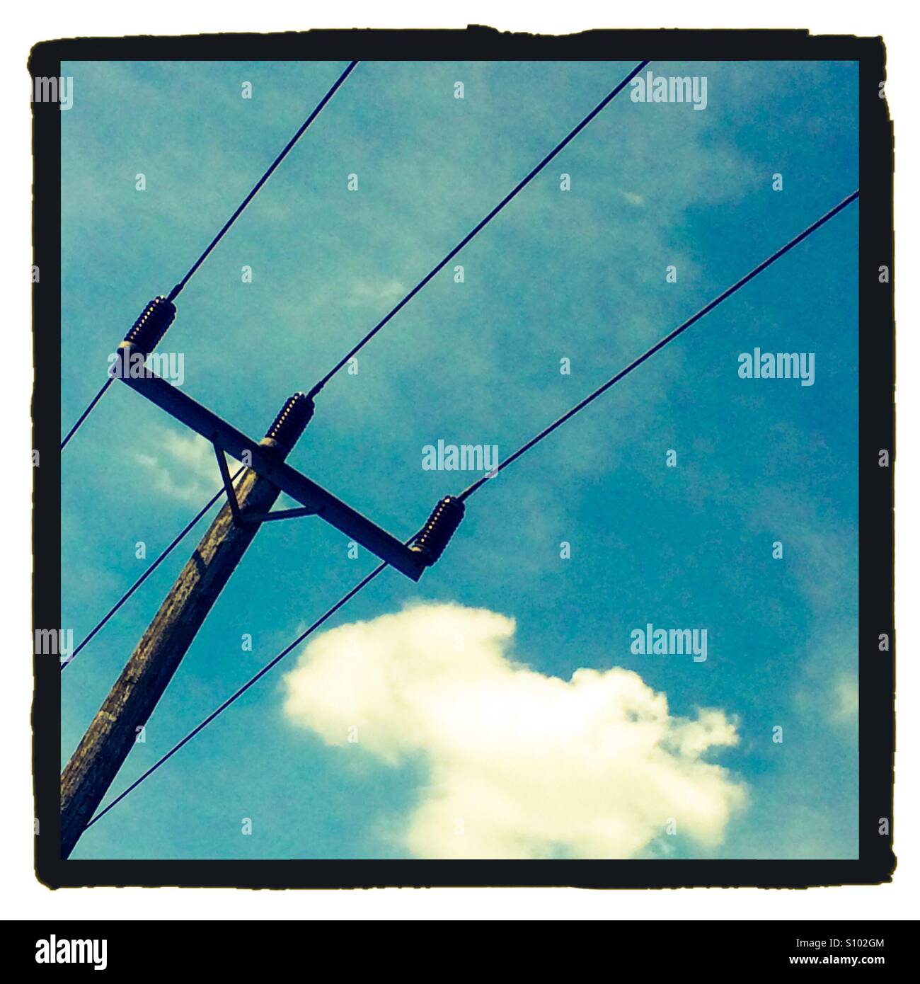 View looking up at telegraph pole and wires with blue sky and white ...